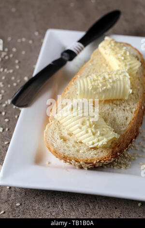 Piece of bread with butter curls on plate, closeup Stock Photo - Alamy
