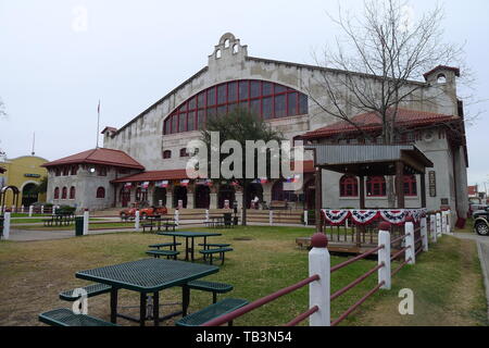 The historic building of Cowtown Coliseum and a green tree against a ...