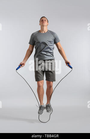 Sporty young man with jumping rope near light wall Stock Photo - Alamy