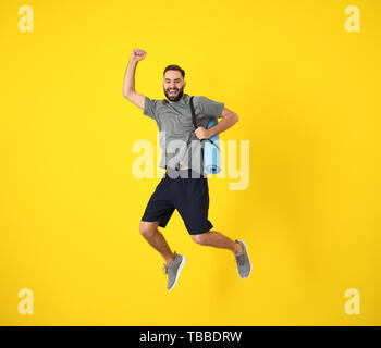 Young sporty man jumping against color background Stock Photo - Alamy