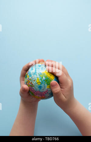 Child holding a small globe in hand on white background Stock Photo - Alamy