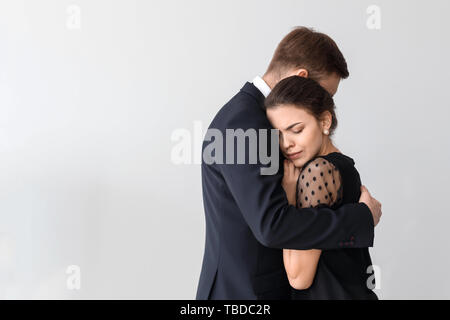 Couple pining after their relative on light background Stock Photo - Alamy