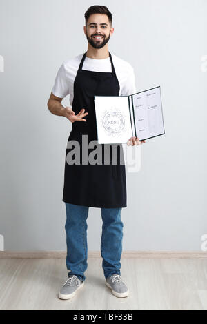 Waiter with menu near light wall Stock Photo - Alamy
