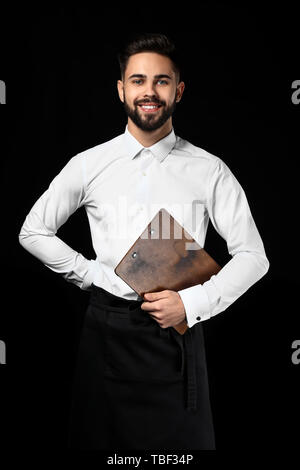 Handsome waiter with menu on dark background Stock Photo - Alamy