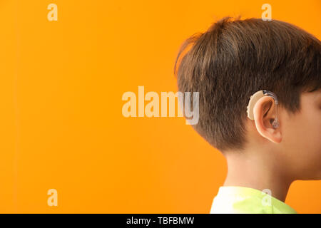 Little boy with hearing aid on color background Stock Photo - Alamy