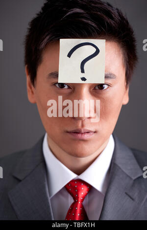 Emotional man with question mark sticker on forehead against light ...
