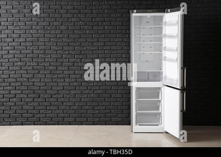 Modern fridge near dark brick wall Stock Photo - Alamy