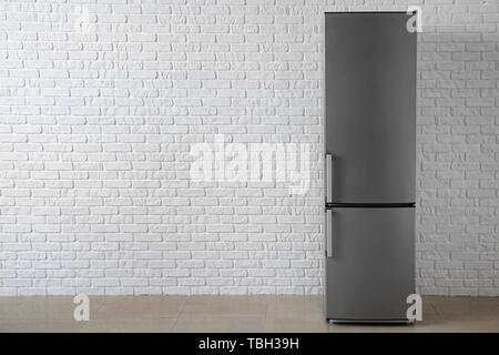 Modern refrigerator near white brick wall, space for text Stock Photo ...