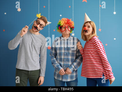 Funny friends with party decor for April Fools' Day on color background ...