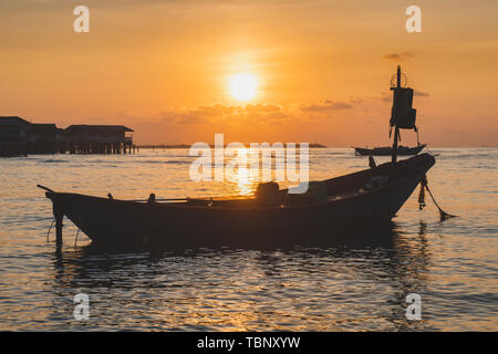 Wooden fishery boat floting on the sea with sunset time low lighting ...