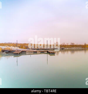 Gleaming lake with reflections of lush grasses and cloudy sky on its ...