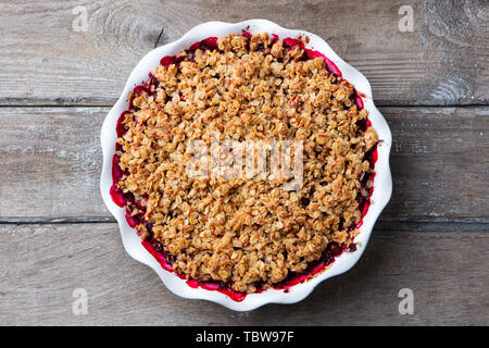 Berry crumble, crisp in baking dish on a dark background. Top view ...