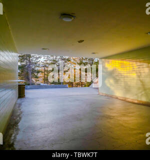 Passageway underneath a building with view of lush trees and sunny ...