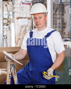 Male contractor looking at room and determining scope of building work ...