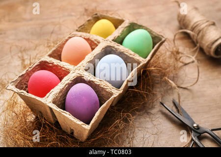 Package with beautiful Easter eggs, scissors and threads on wooden ...