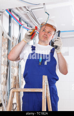 confident electrician mounting electrical wiring inside building Stock ...