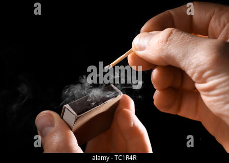 Man striking match on dark background Stock Photo - Alamy