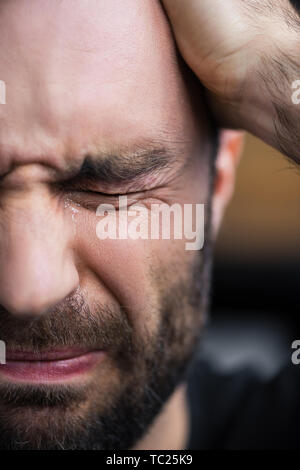 depressed bearded man crying with closed eyes and holding hand on head ...