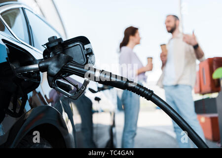 Woman refueling black automobile at gas station with blue fuel pump ...
