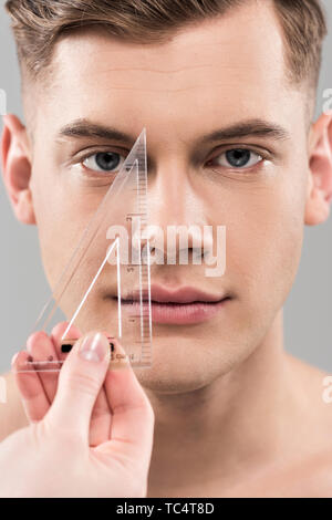 cropped view of plastic surgeon measuring face with ruler isolated on ...