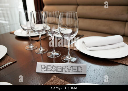 Wooden reserved plate on an arranged restaurant table, toned image ...