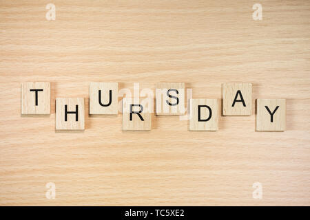 The word Thursday, spelt out using wooden tiles on a wood effect ...