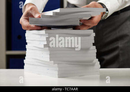 Businessman working at an office, reads stack of books and reports ...