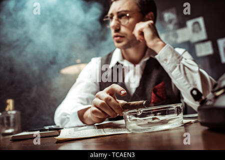 Detective in glasses smoking cigar and reading newspaper with magnifier ...