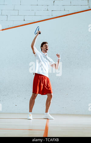 Full length view of happy squash player with racket showing yes gesture ...
