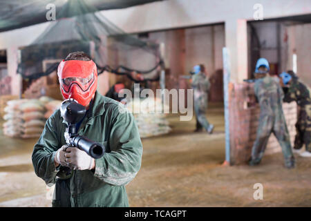 Player in red mask is targeting in enemy in a battlefield in paintball ...