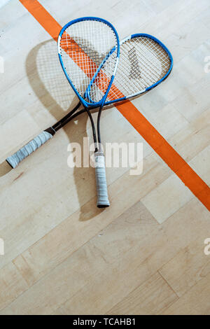 Two squash rackets on wooden floor in four-walled court Stock Photo - Alamy
