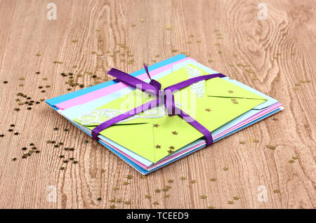Bunch of color envelopes with ribbon and confetti on wooden background ...