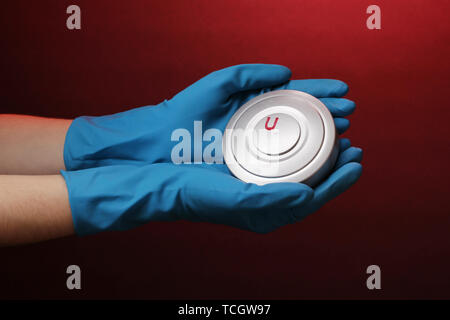 Uranium in hand on red background Stock Photo - Alamy