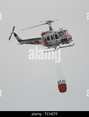 A Cal Fire helicopter flying around with water bucket in lake berryessa ...
