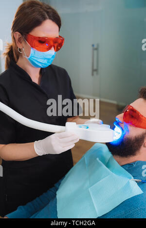 Teeth whitening for patient. Laser bleaching teeth in dental clinic ...