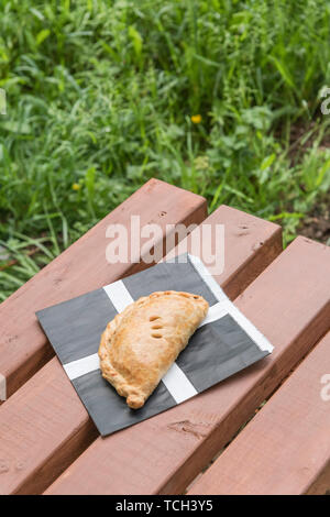 Cornish pasty sitting on paper food bag decorated with St. Piran's flag ...