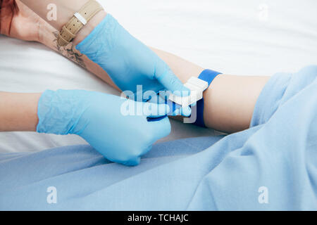 partial view of doctor using tourniquet for blood test in hospital ...