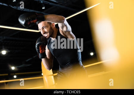 low angle view of bearded and strong man boxing in gym with get up ...