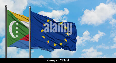 European Union and Comoros flag waving in the wind against white cloudy ...