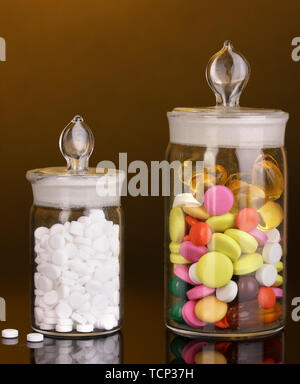 Capsules and pills in receptacles on orange background Stock Photo - Alamy