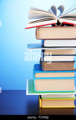 Stack of interesting books and magazines on wooden table on blue ...