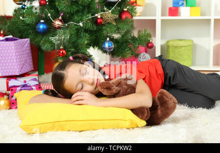 Little girl sleeping near Christmas tree in room Stock Photo - Alamy