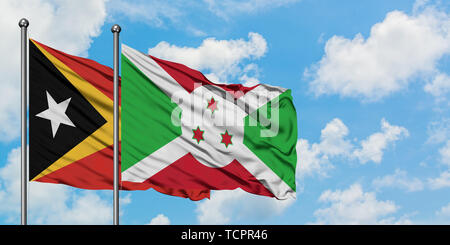 Burundi and East Timor flag waving in the wind against white cloudy ...