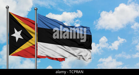 Estonia and East Timor flag waving in the wind against white cloudy ...