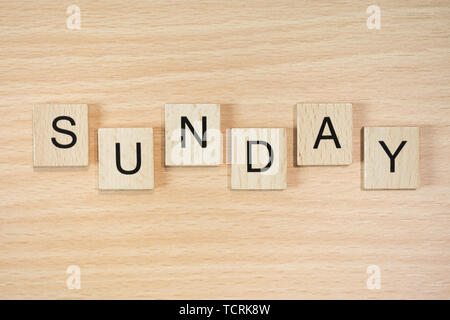 The word Sunday, spelt out using wooden tiles on a wood effect ...