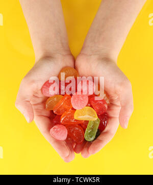 Hands full of sweets on yellow background Stock Photo - Alamy