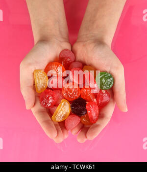 Hands full of sweets on pink background Stock Photo - Alamy