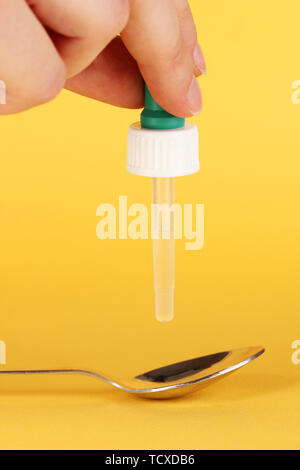 Medical droplet in spoon on yellow background Stock Photo - Alamy