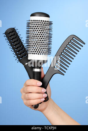 Three combs in female hand on color background Stock Photo - Alamy