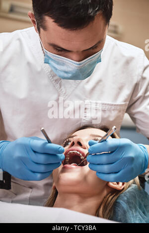 Dentist checking client teeth using mouth mirror and sickle probe Stock ...